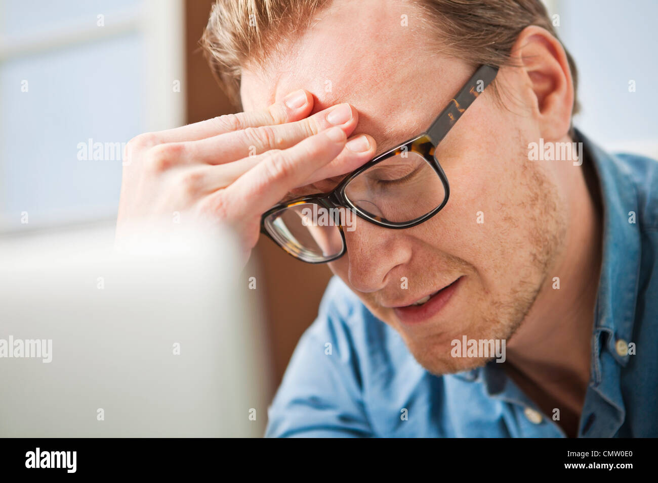 Man sitting at laptop, looking stressed Stock Photo - Alamy