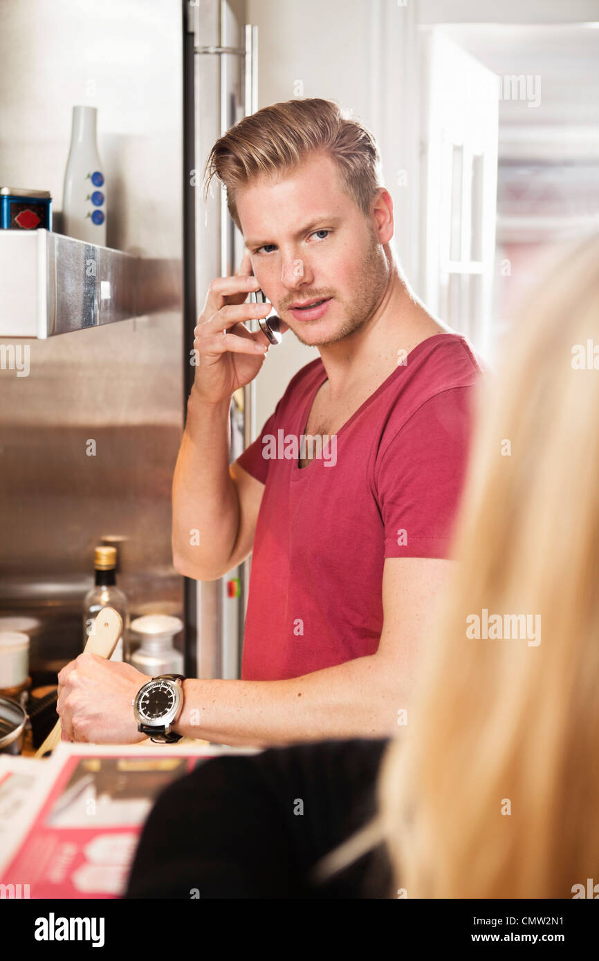 Guy cooking and making a phone call while looking at girlfriend Stock ...