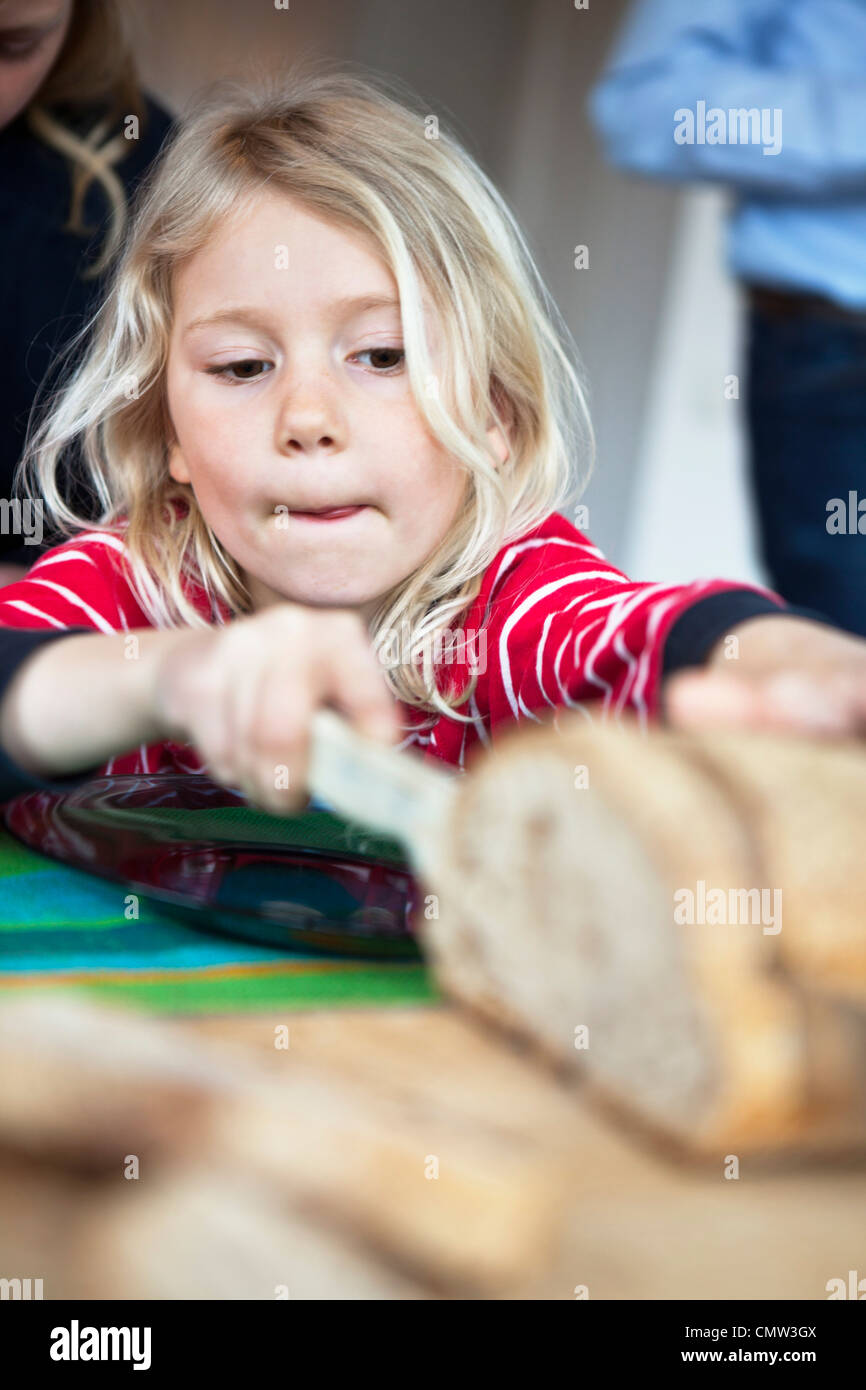 Girl cutting loaf of bread Stock Photo - Alamy