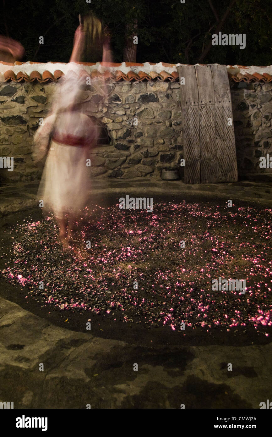 A woman dances with bare feet on the glowing hot embers, a ritual fire ...