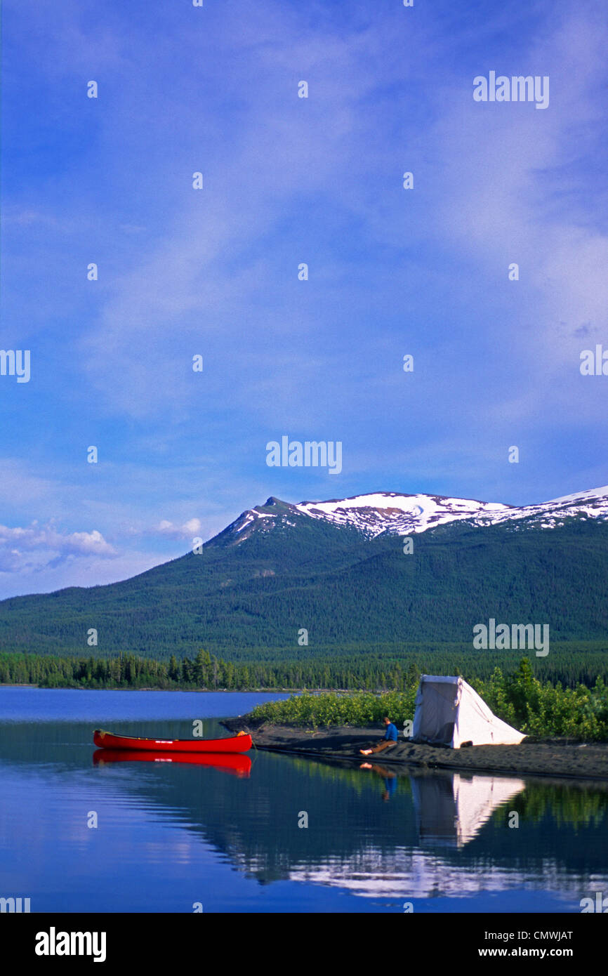 Man Relaxing by his Tent and Canoe while Camping along the Shores of ...