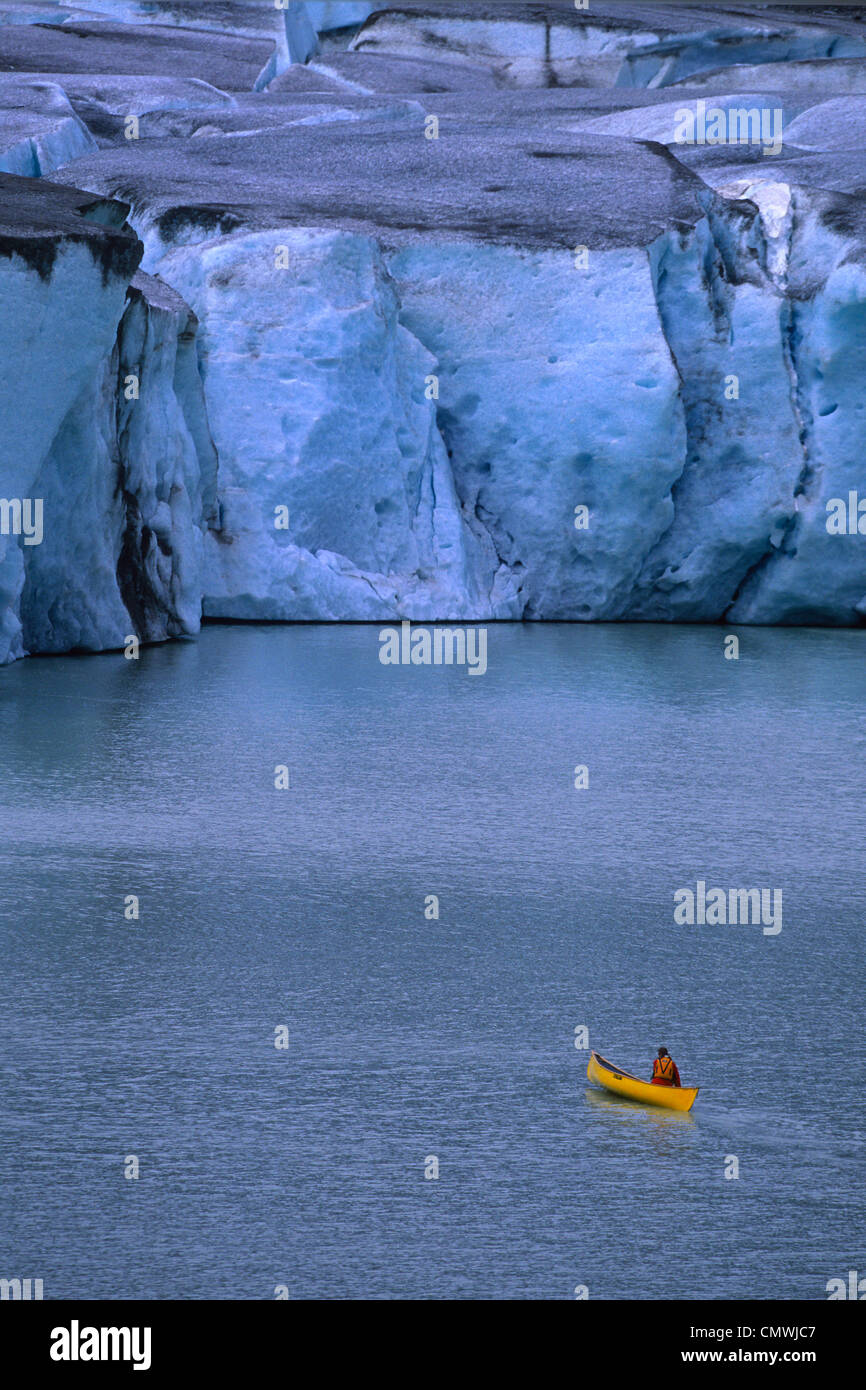 Canoeist passing the Wall of the Llewellyn Glacier, near Atlin Lake ...