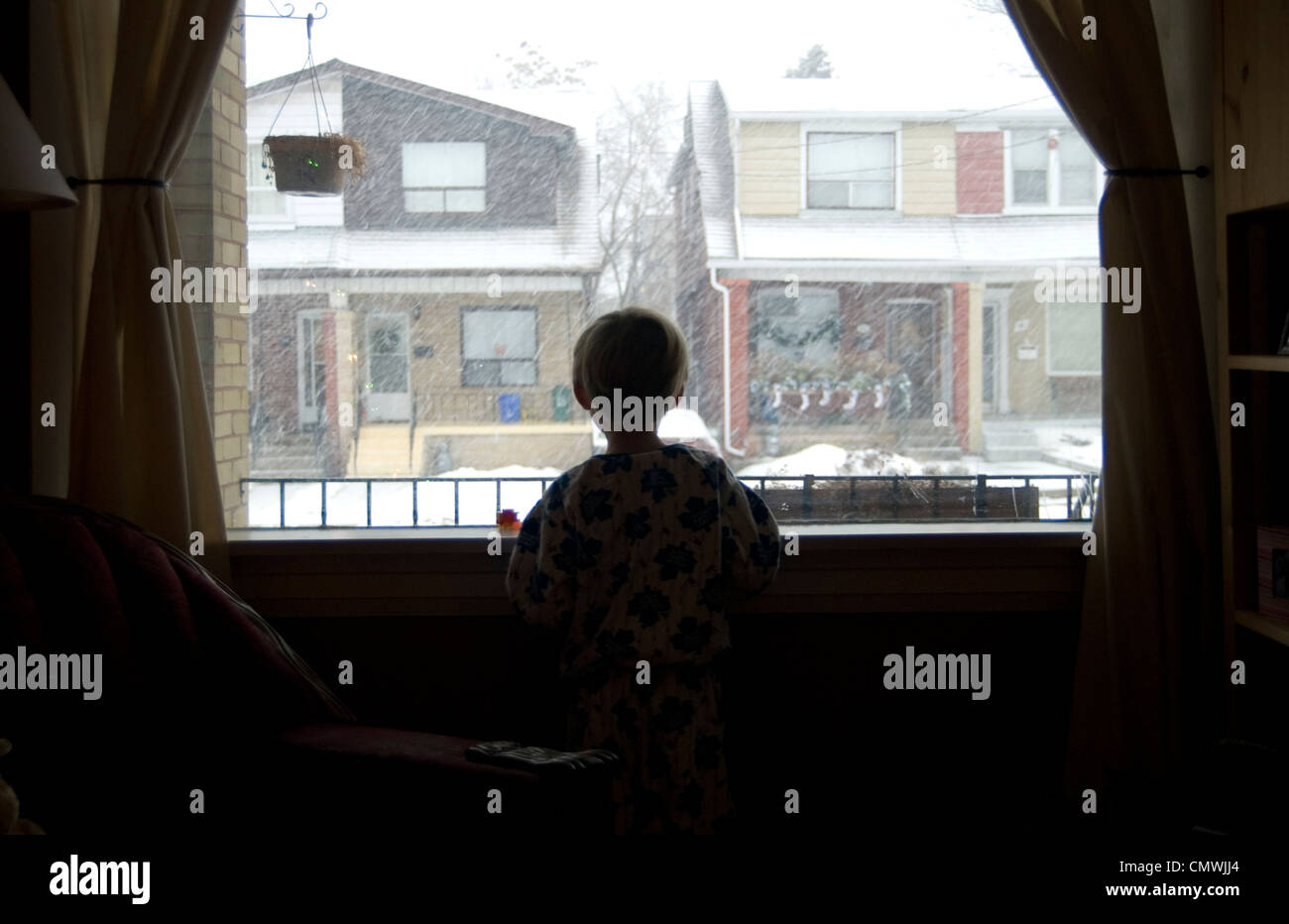 Young Boy Looking through a Window at Falling Snow Stock Photo - Alamy