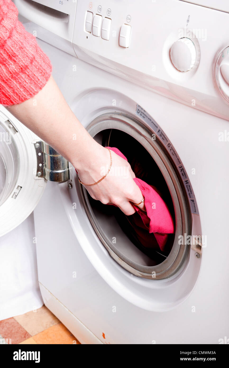 Young woman loading the washing machine Stock Photo - Alamy