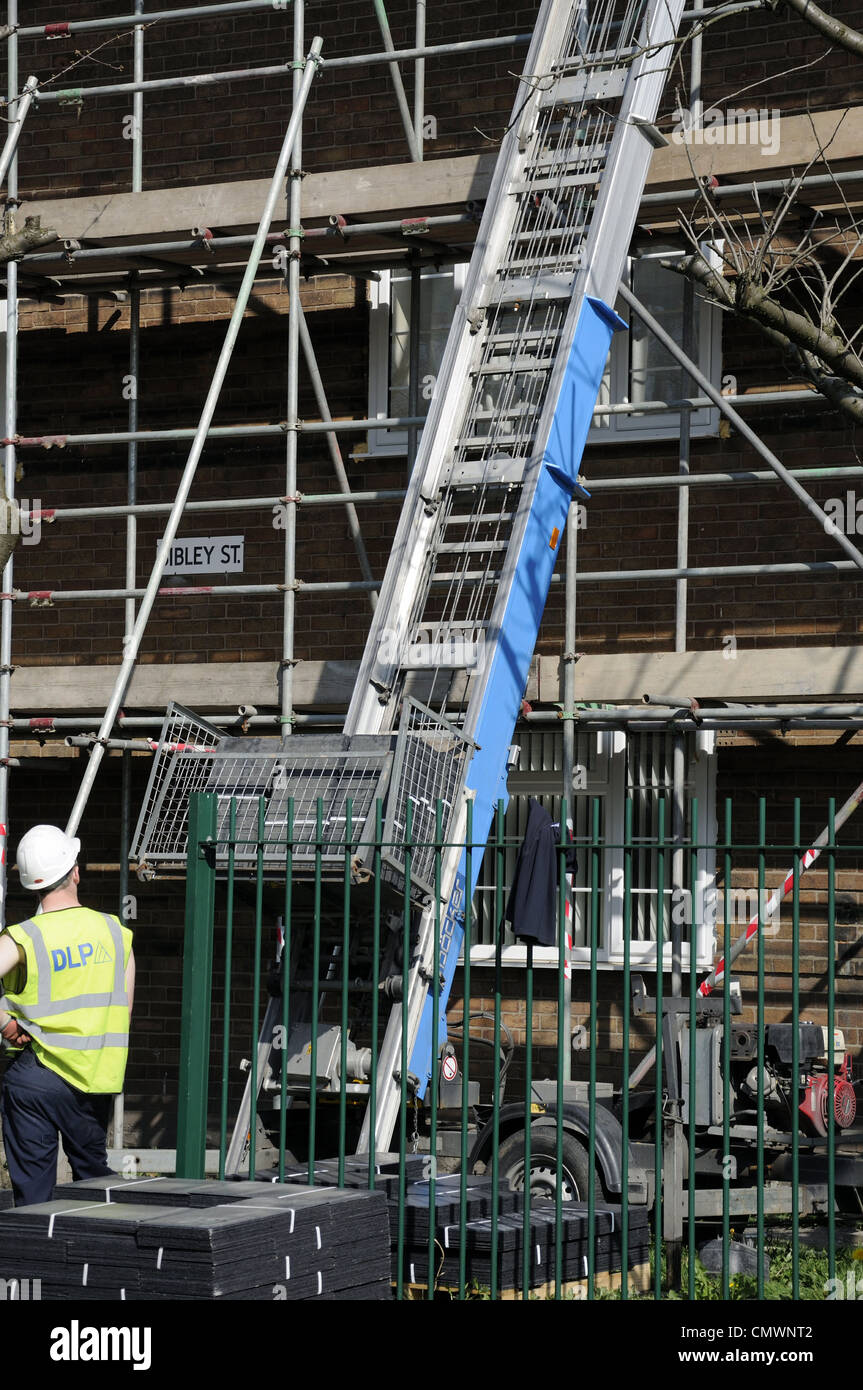 New load of roof tiles on way up to workmen at top of scaffolding Stock ...