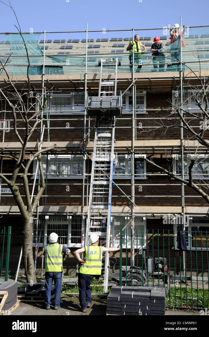 Workmen putting new roof tiles on block of houses waiting for new load ...