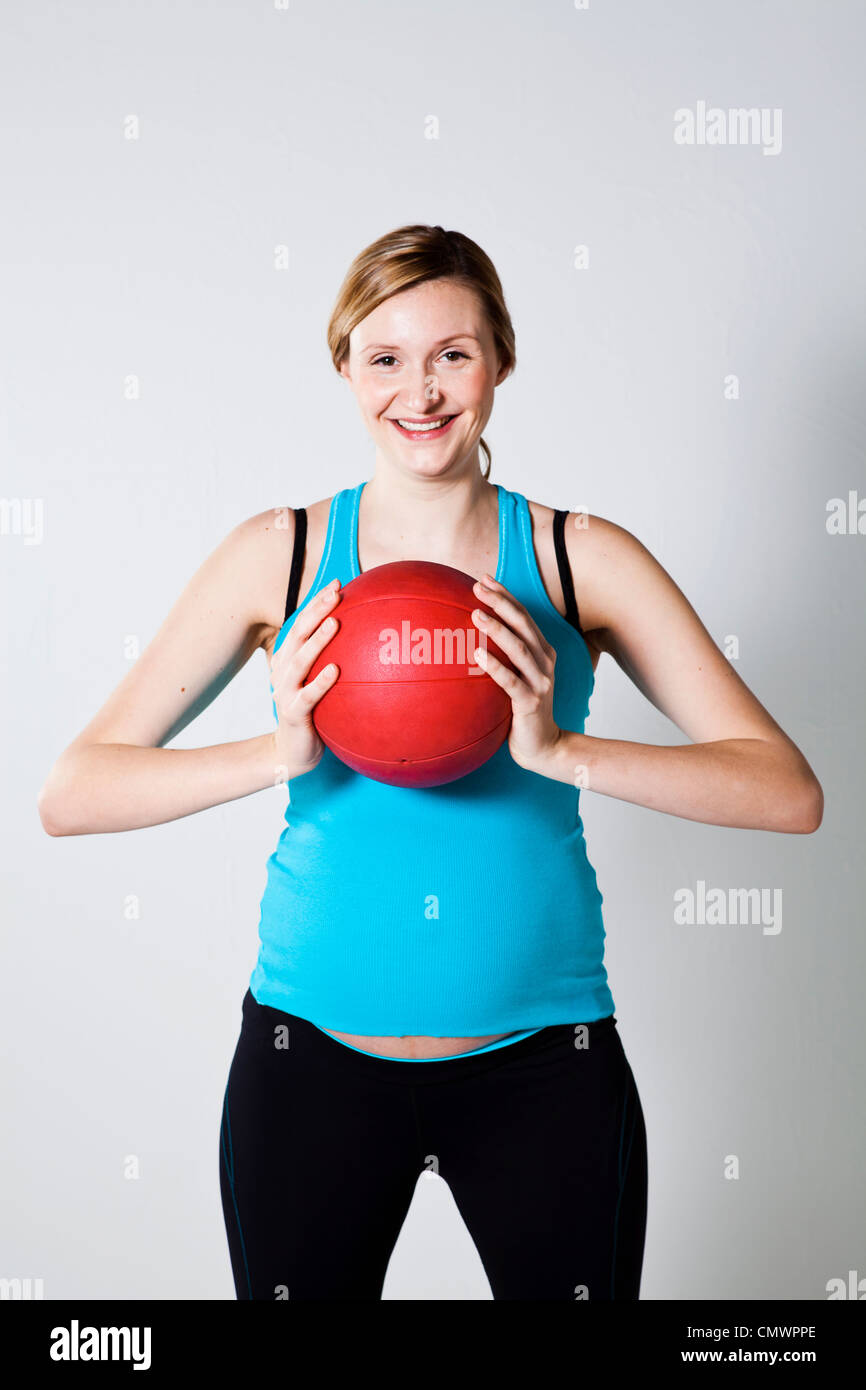 Pregnant woman holding a red exercise ball next to her chest Stock ...
