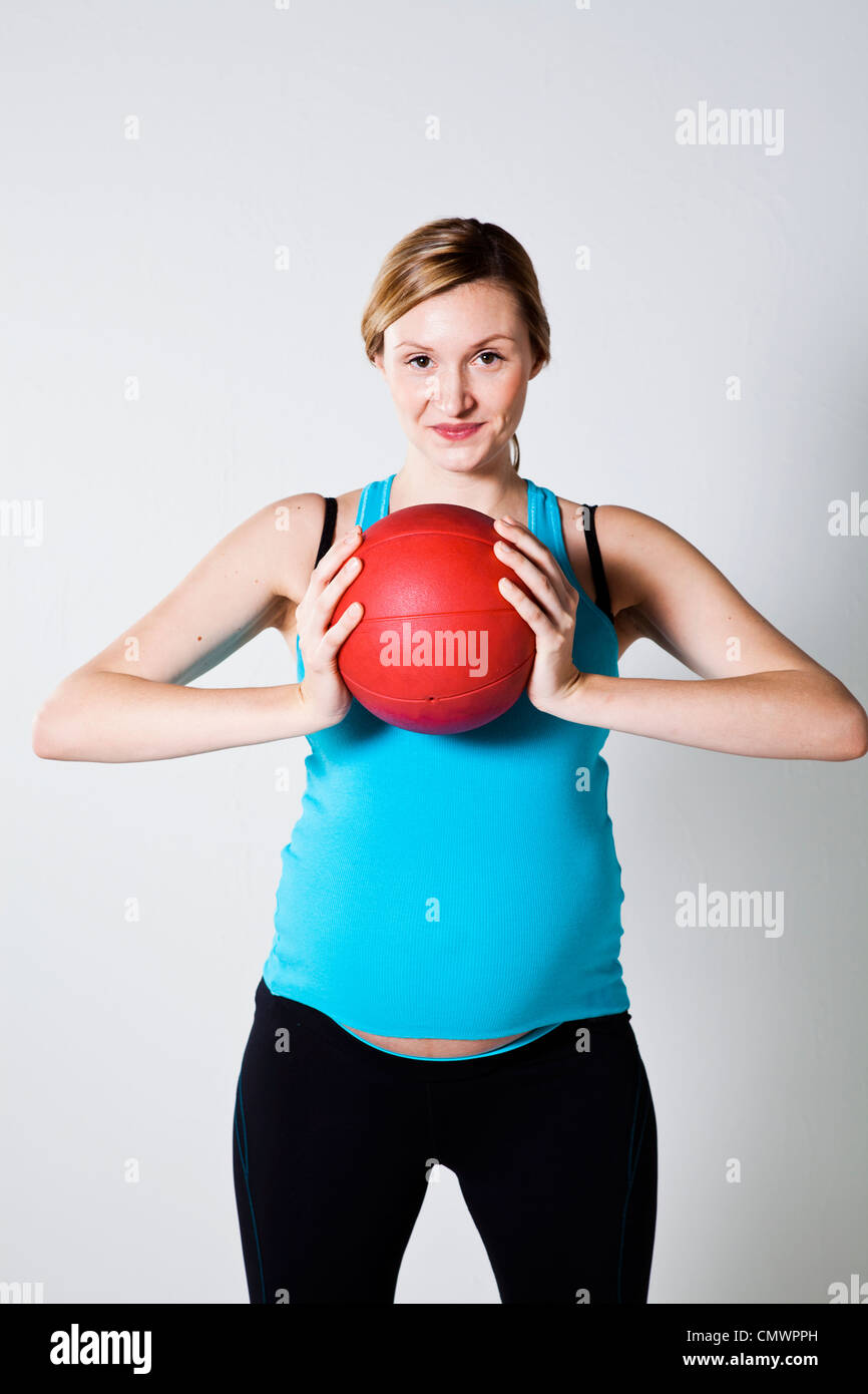 Pregnant woman holding a red exercise ball next to her chest Stock ...