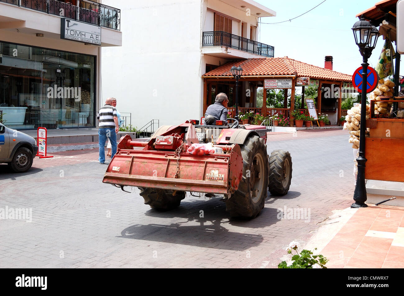 Busy Greek farmer drives his tractor through the Spili village, Crete ...
