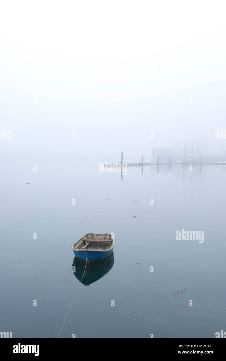 A small boat sitting in a calm, empty and misty harbor Stock Photo - Alamy