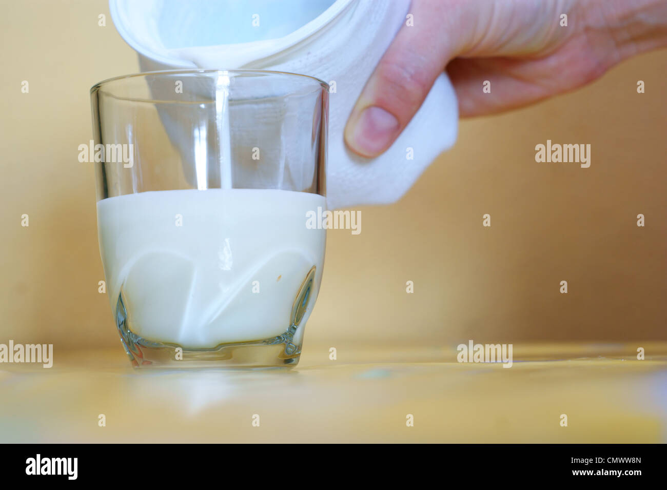 pouring kefir to glass, yellow background Stock Photo - Alamy