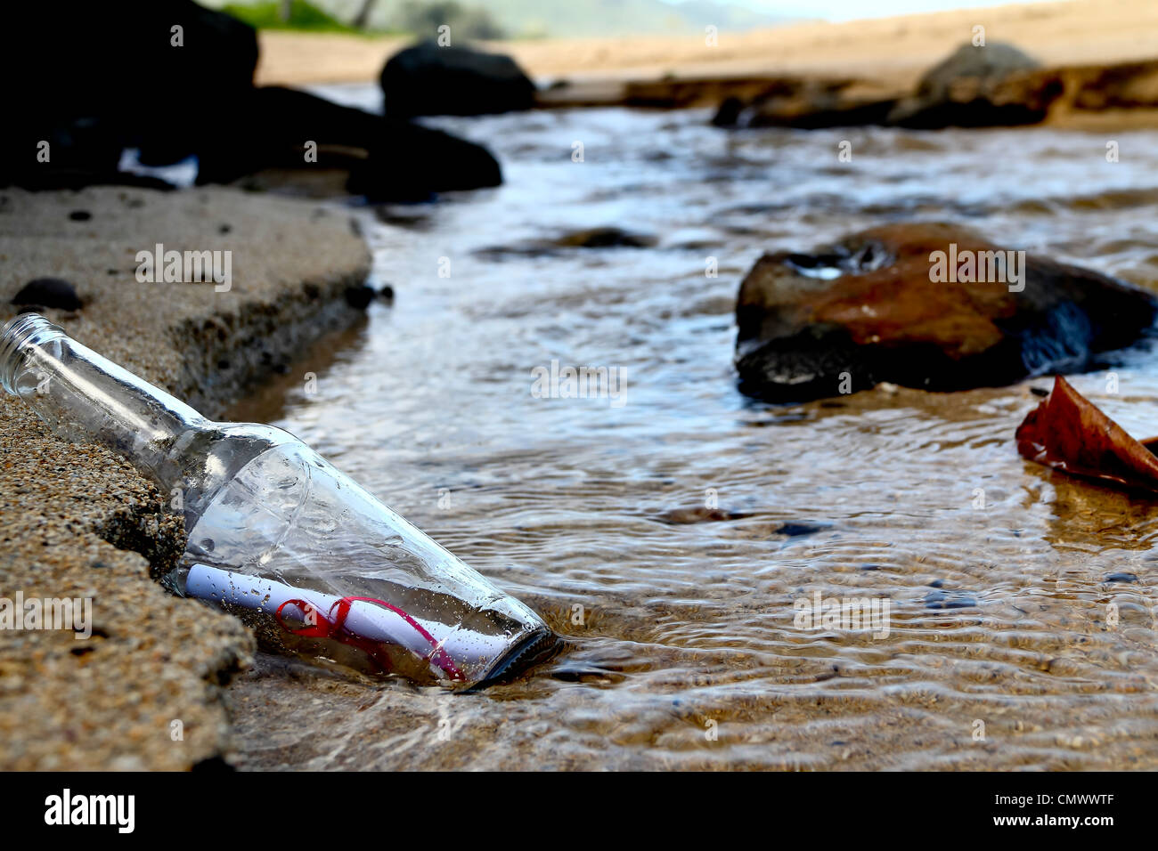 Glass bottle with note in water on beach Stock Photo - Alamy