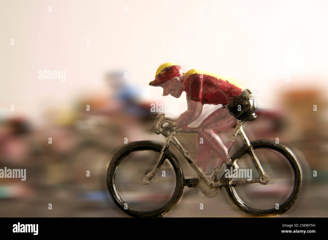 A tiny cyclist dressed in red races forward on a bicycle. The ...