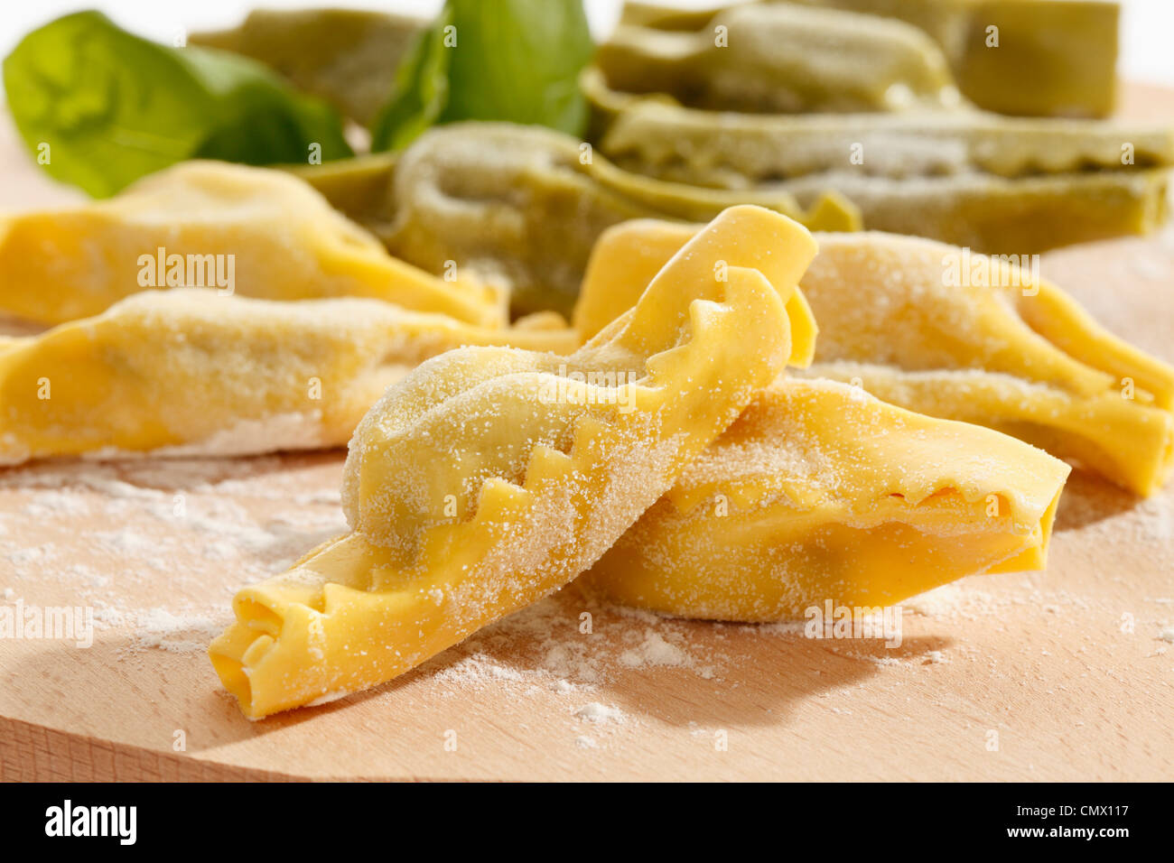 Candy shape pasta with flour and basil leaf on chopping board Stock ...
