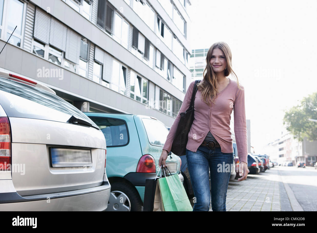 Germany, Cologne, Young woman with shopping bags, smiling, portrait ...