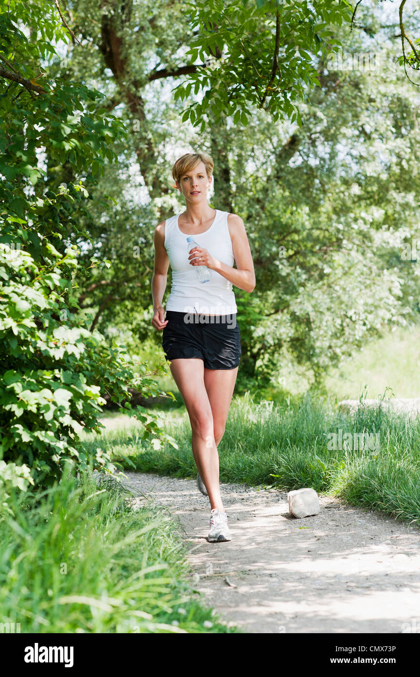Germany, Munich, Mid adult woman jogging along Isar river, portrait ...