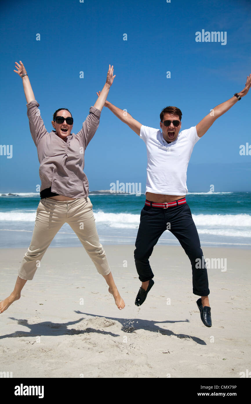 Couple jumping on beach Stock Photo - Alamy