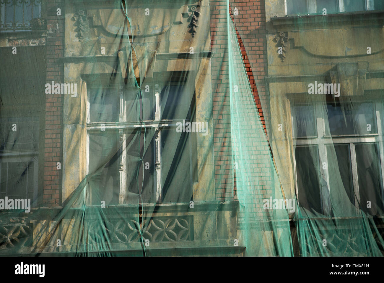 Facade of an decay building covered by protective green mesh against ...