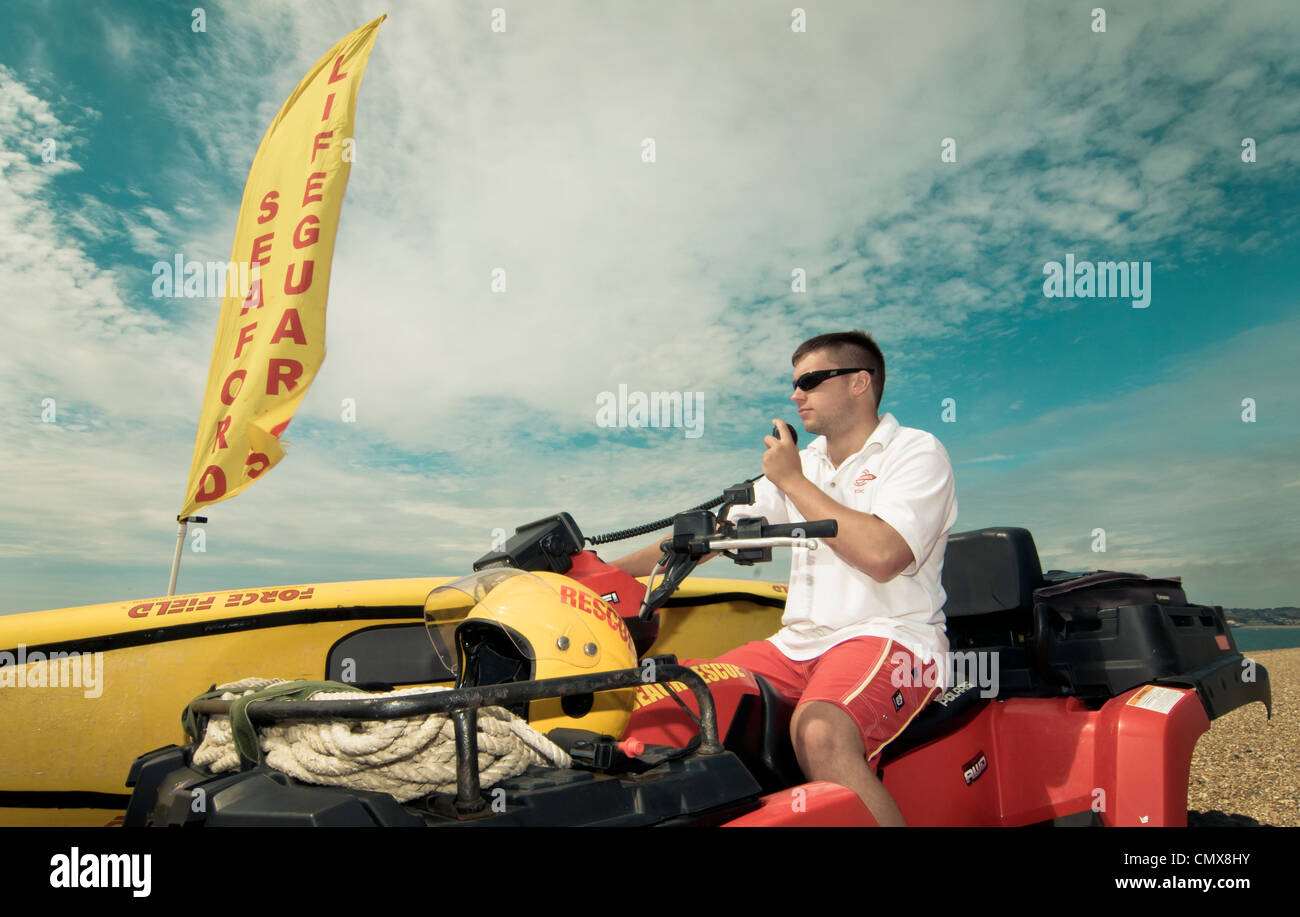 Lifeguard sat on quad bike with canoe and flag patrolling beach Stock ...