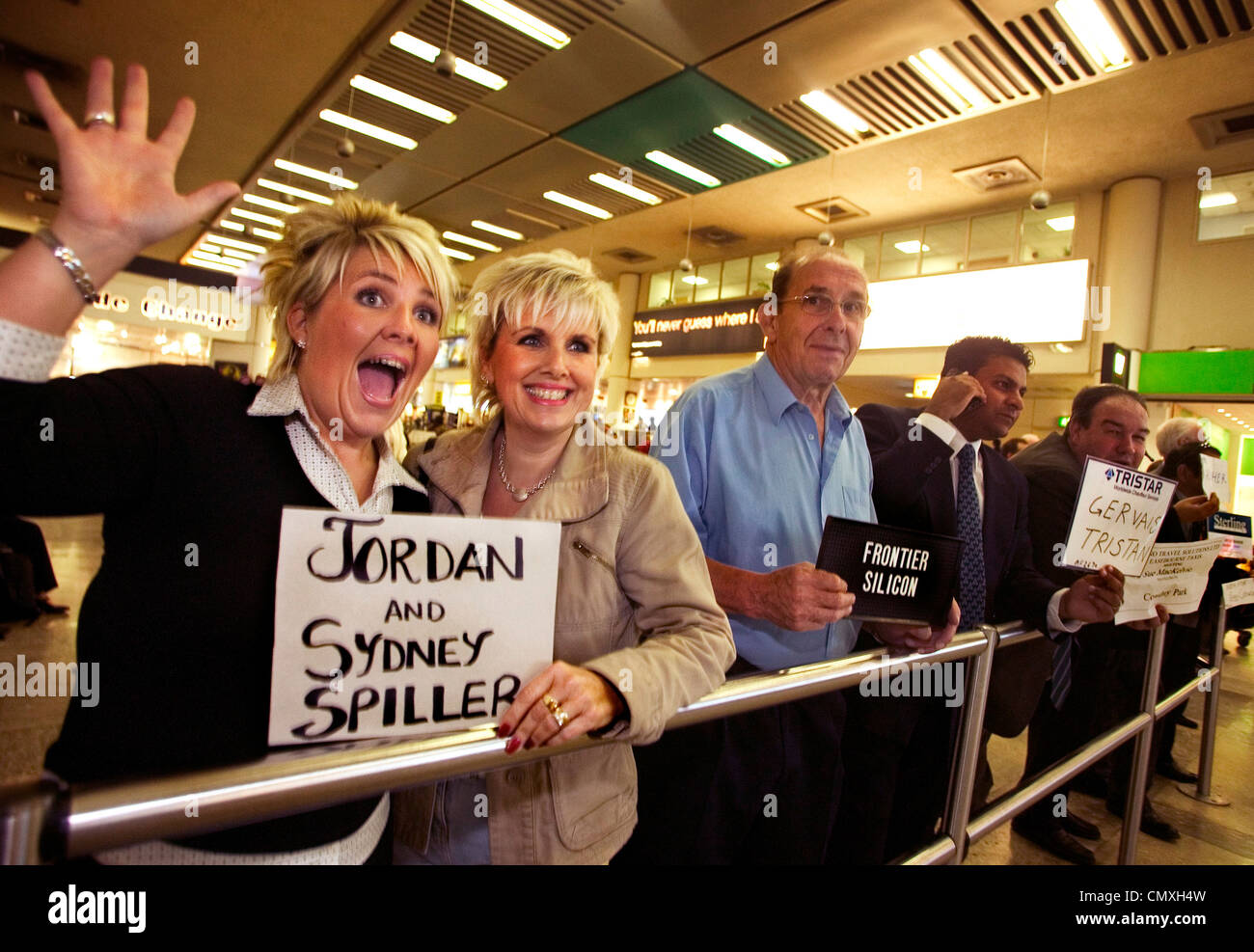 family waiting at arrivals gate in airport with welcoming name sign ...