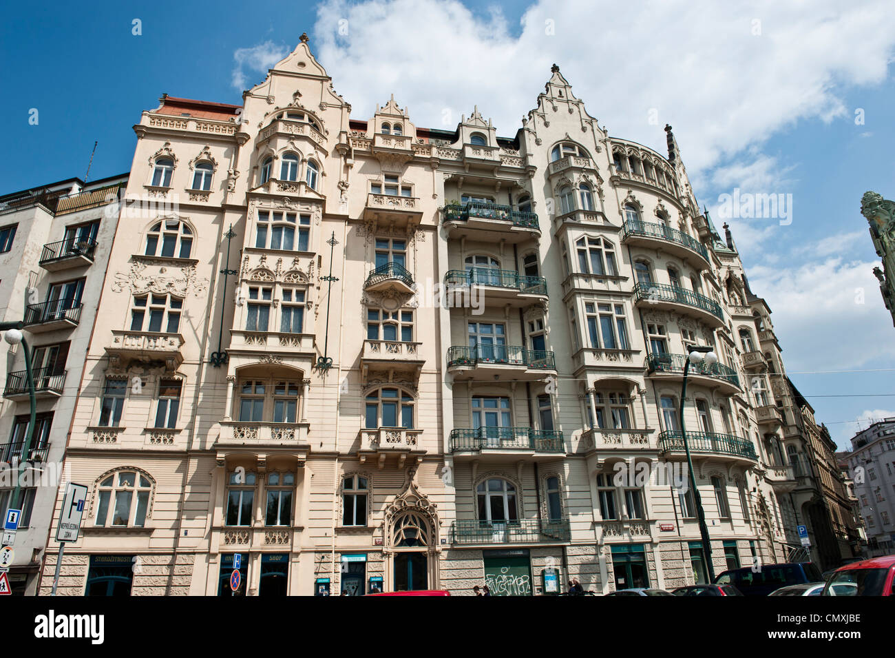 Cutoff view of cars on the street outside of a huge Czech building ...