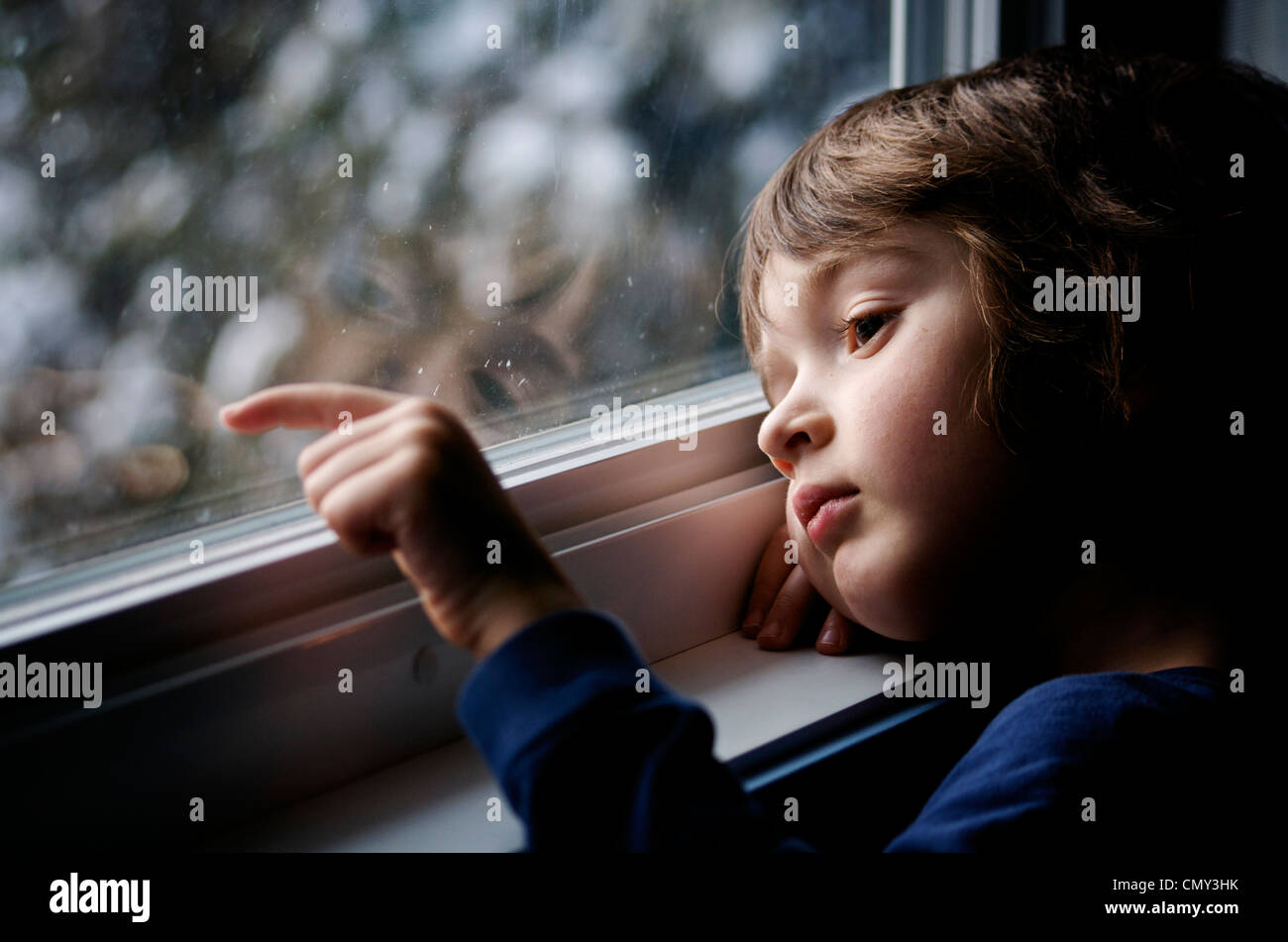 Young boy looking out a window and scratching the glass, Otterburn Park ...