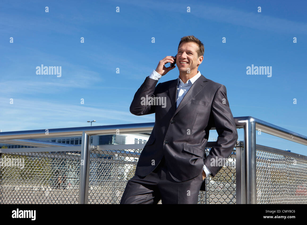 Germany, Bavaria, Munich,Businessman talking on cell phone, smiling ...