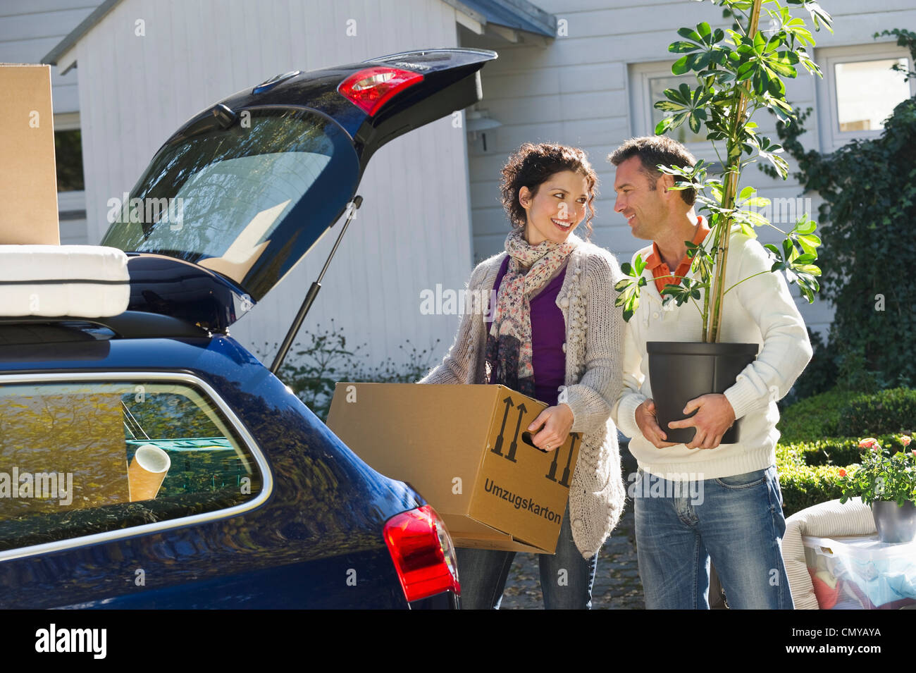 Germany, Bavaria, Grobenzell, Couple loading boxes into car, smiling ...