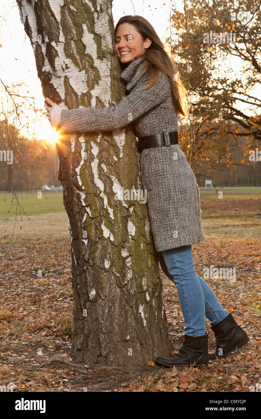 Germany, Berlin, Wandlitz, Mid adult woman hugging tree, smiling Stock ...
