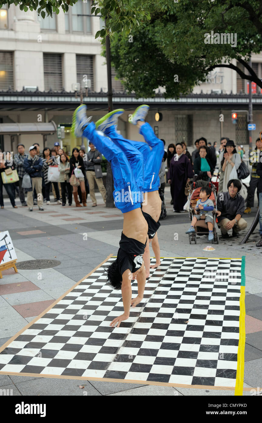 two Japanese street artists doing an acrobatic show in front of ...