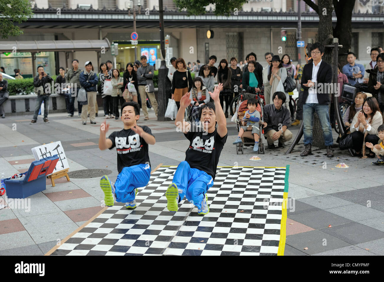 two Japanese street artists doing an acrobatic show in front of ...