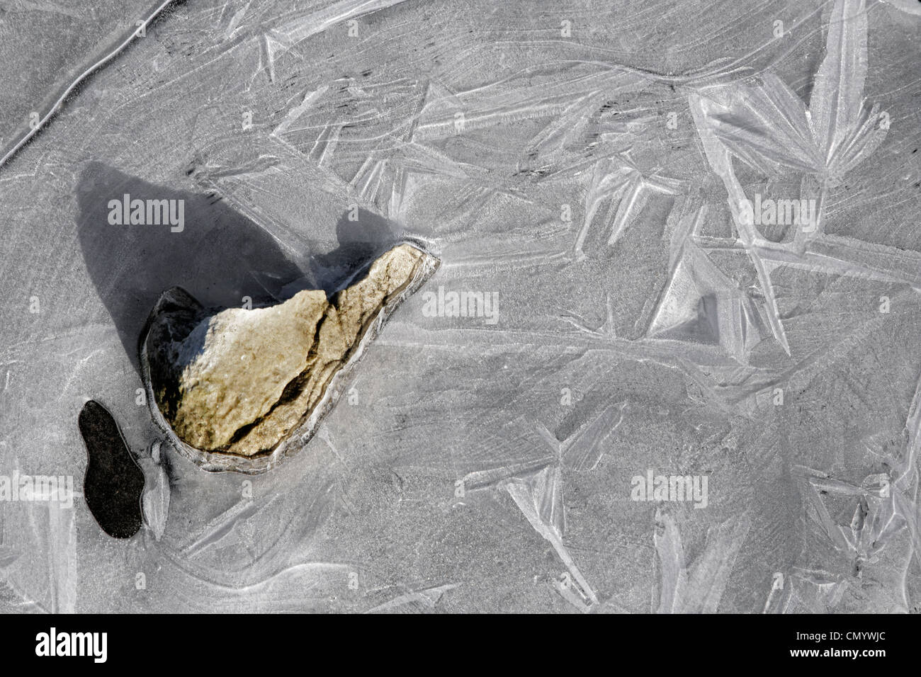 Stones encased in ice, and patterns of ice crystals on a pool of water ...