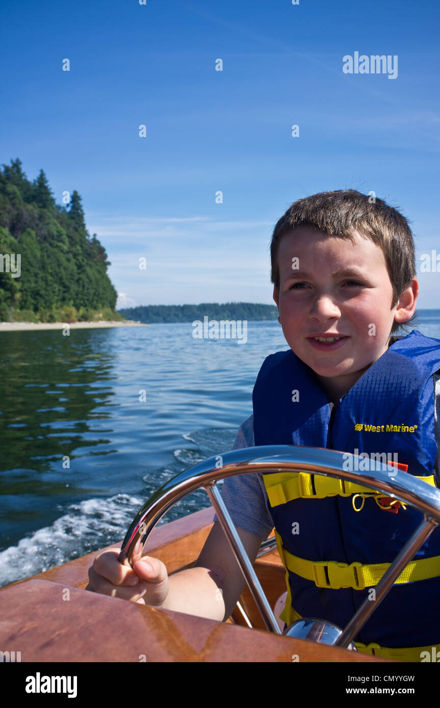 young boy steering motor boat Stock Photo - Alamy