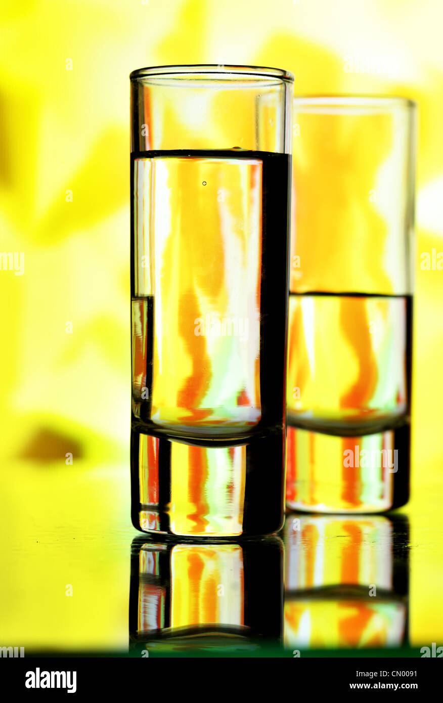 Two glasses of strong alcohol over yellow background Stock Photo - Alamy