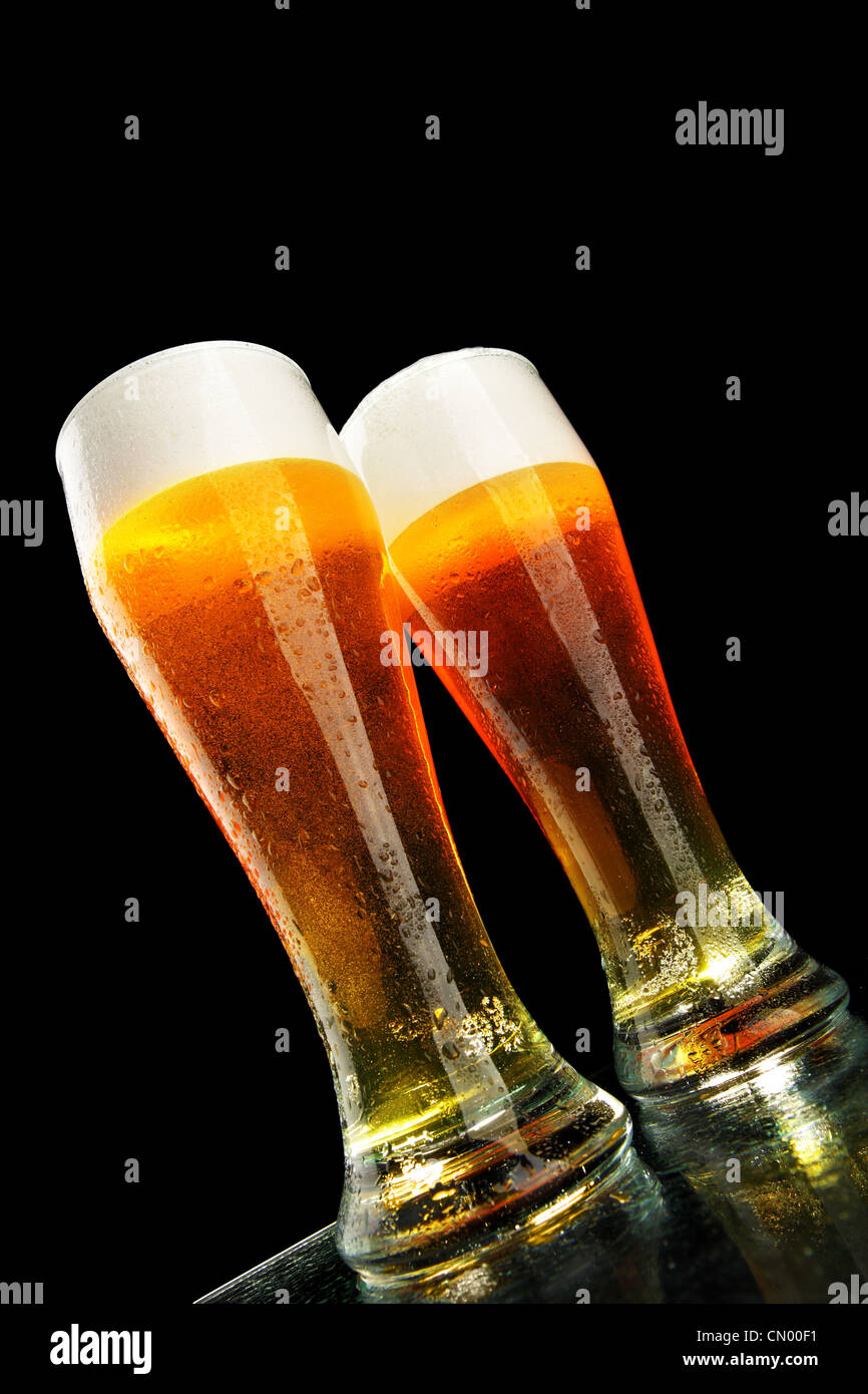 Two glasses of beer with froth over black background Stock Photo - Alamy