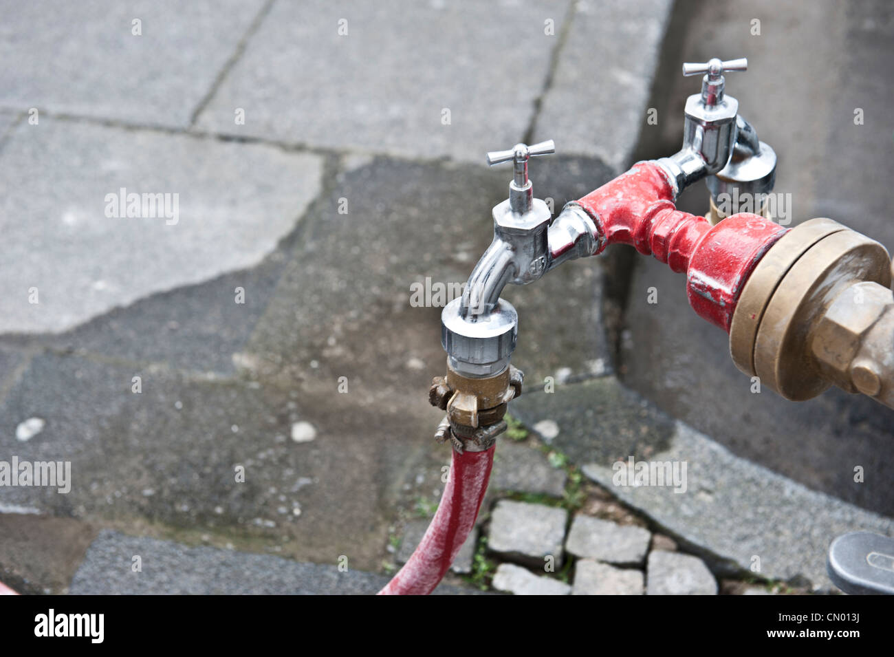 An old, rusty fire hose with water dripping onto the sidewalk Stock ...