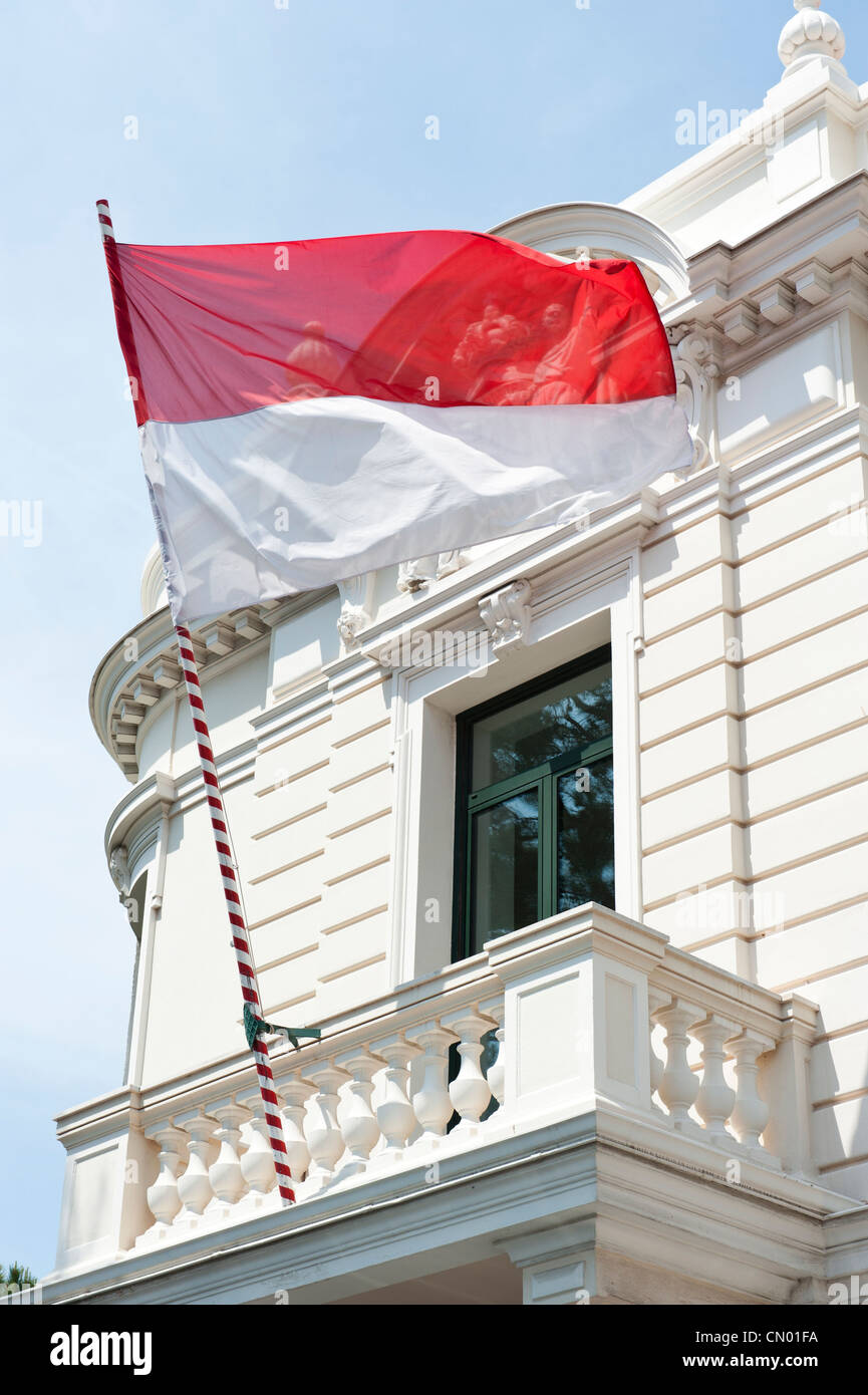 The Monaco flag blowing in the wind on the balcony of a white building ...