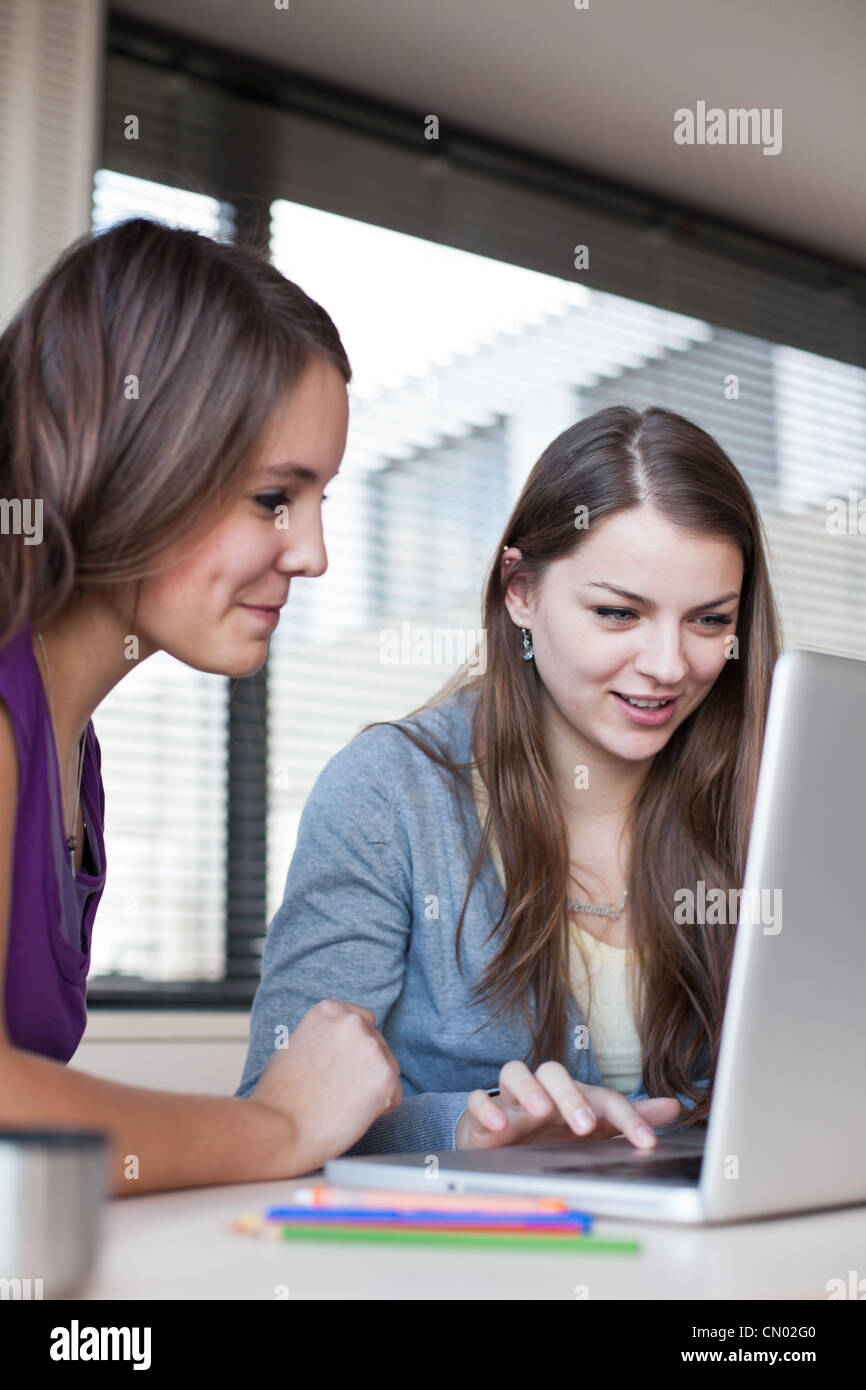 Two female college students working on a laptop computer during class ...