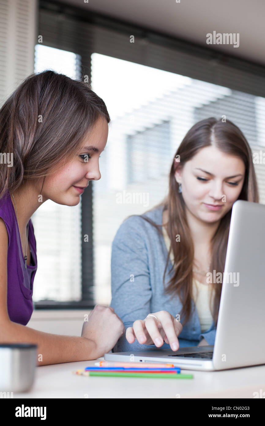 Two female college students working on a laptop computer during class ...