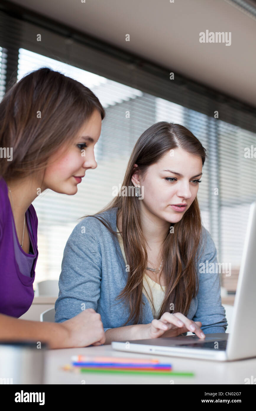 Two female college students working on a laptop computer during class ...