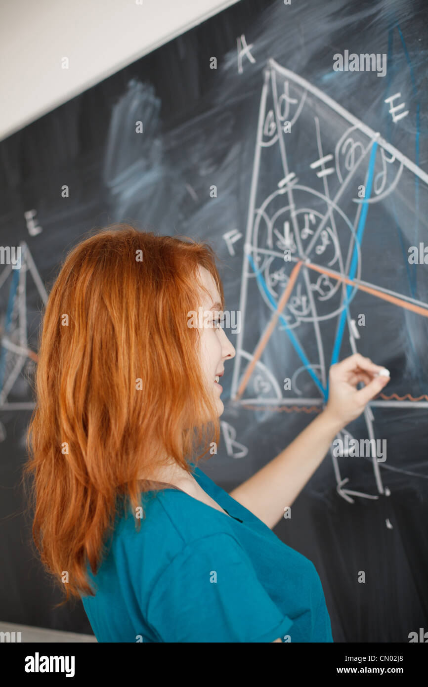 pretty young college student writing on the chalkboard/blackboard ...