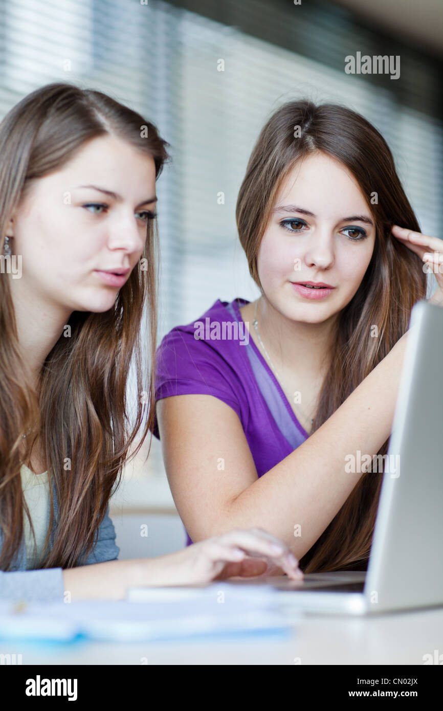 Two female college students working on a laptop computer during class ...