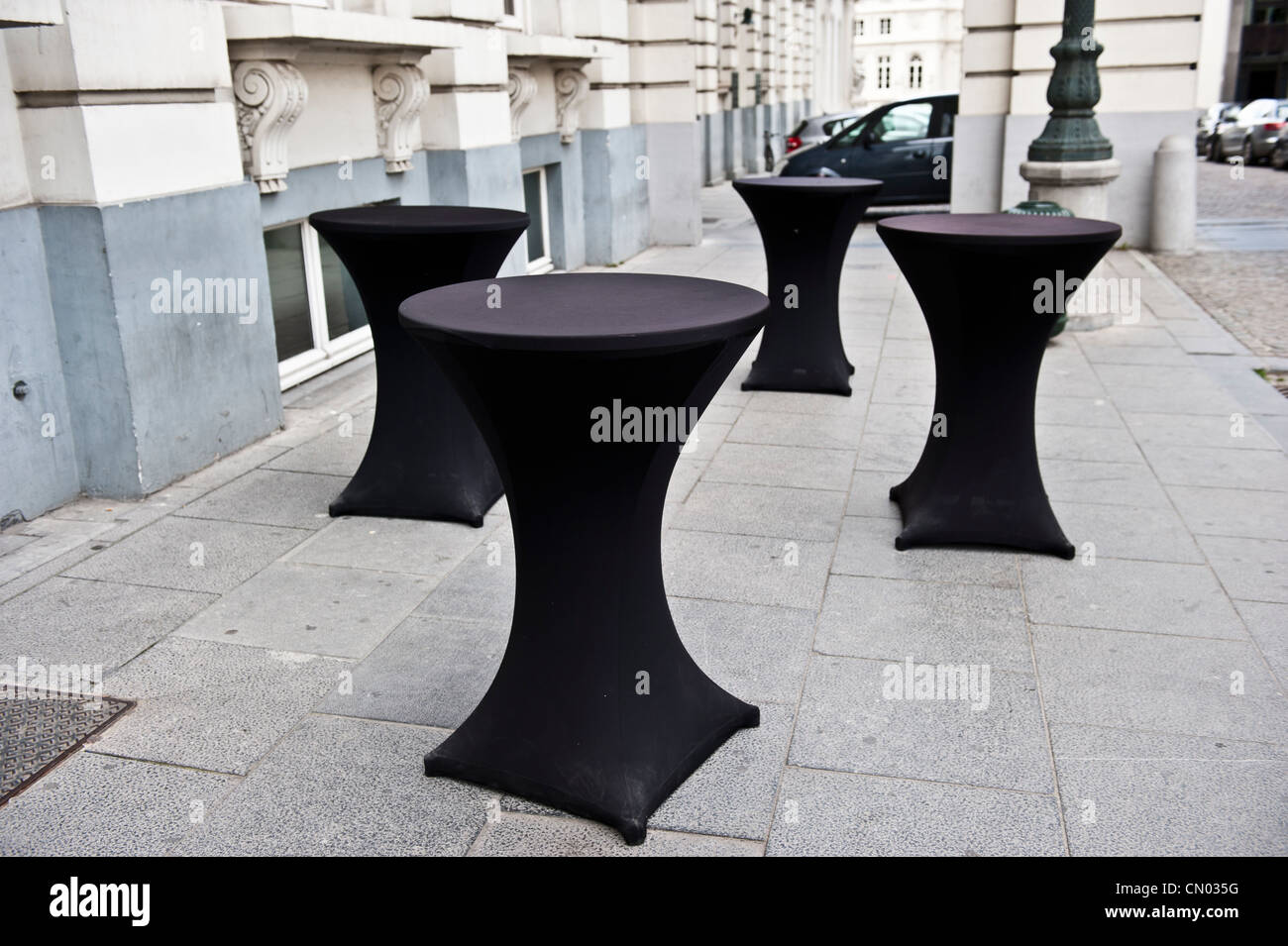 A simple, elegant cocktail reception setup with tables covered in black ...