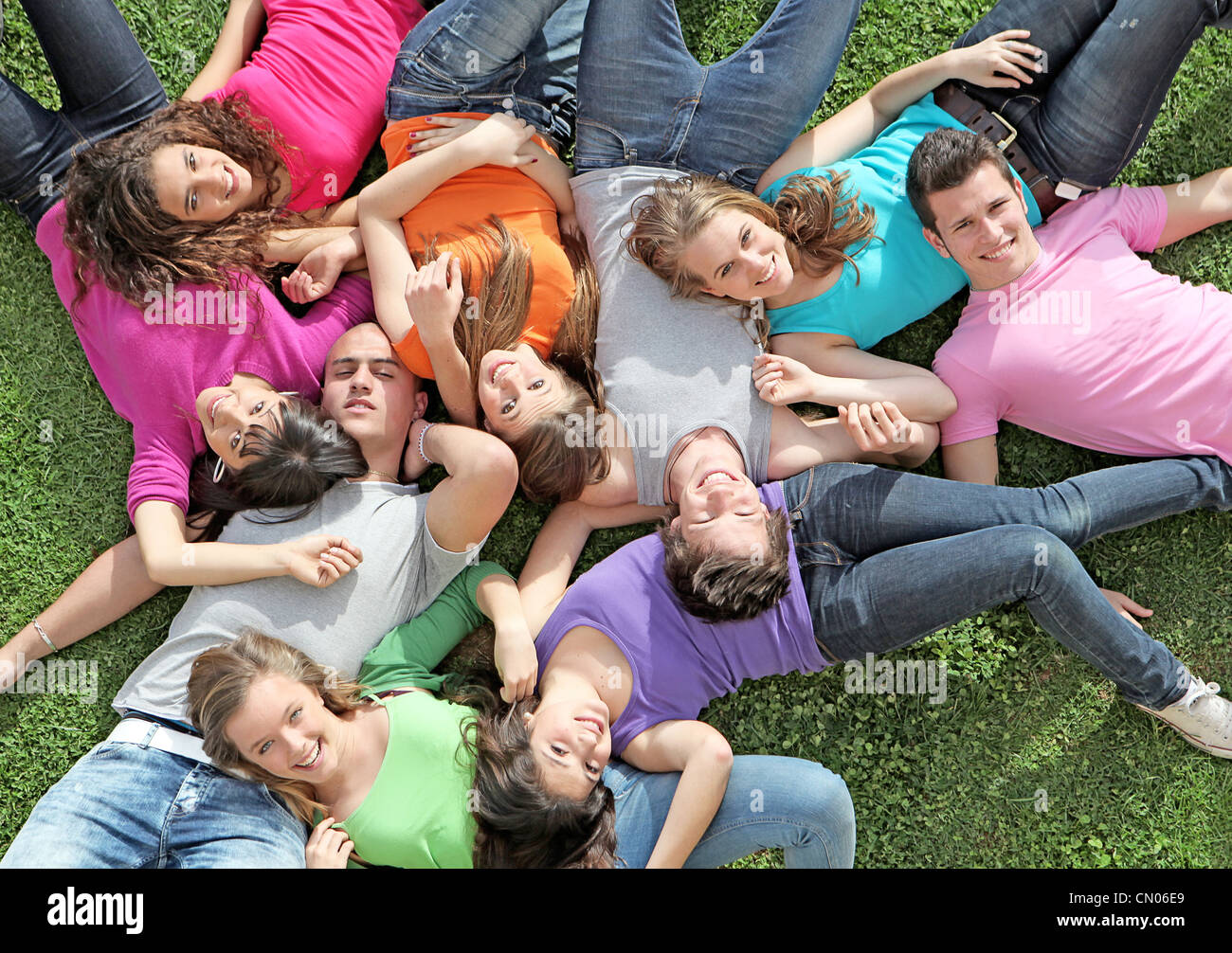 group of happy healthy kids laying outdoors on grass at summer camp ...