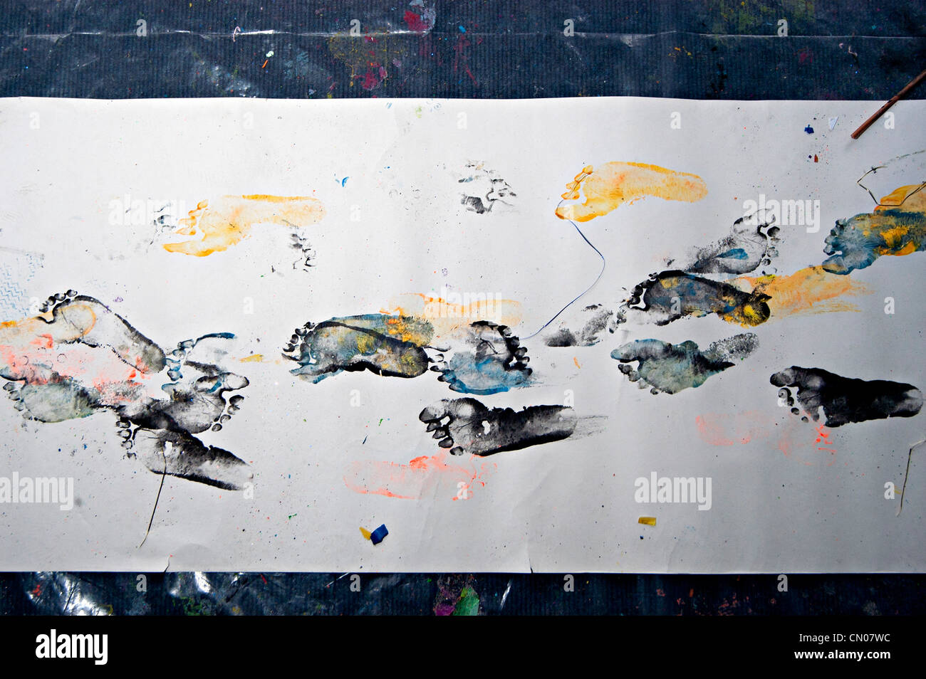 children make paint marks with their feet on a roll of white paper ...