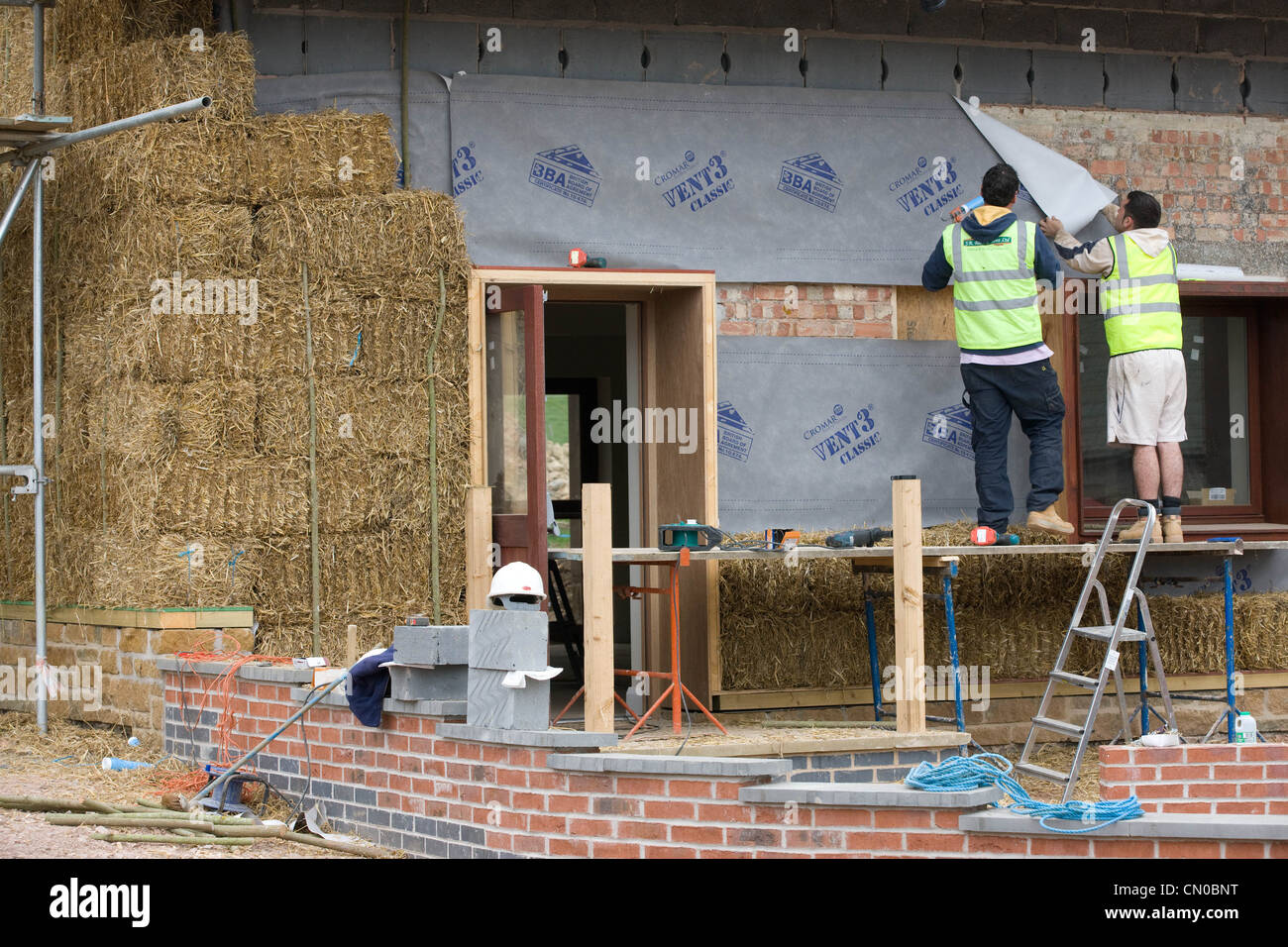 Builders using straw for insulation on a new Eco-friendly building ...