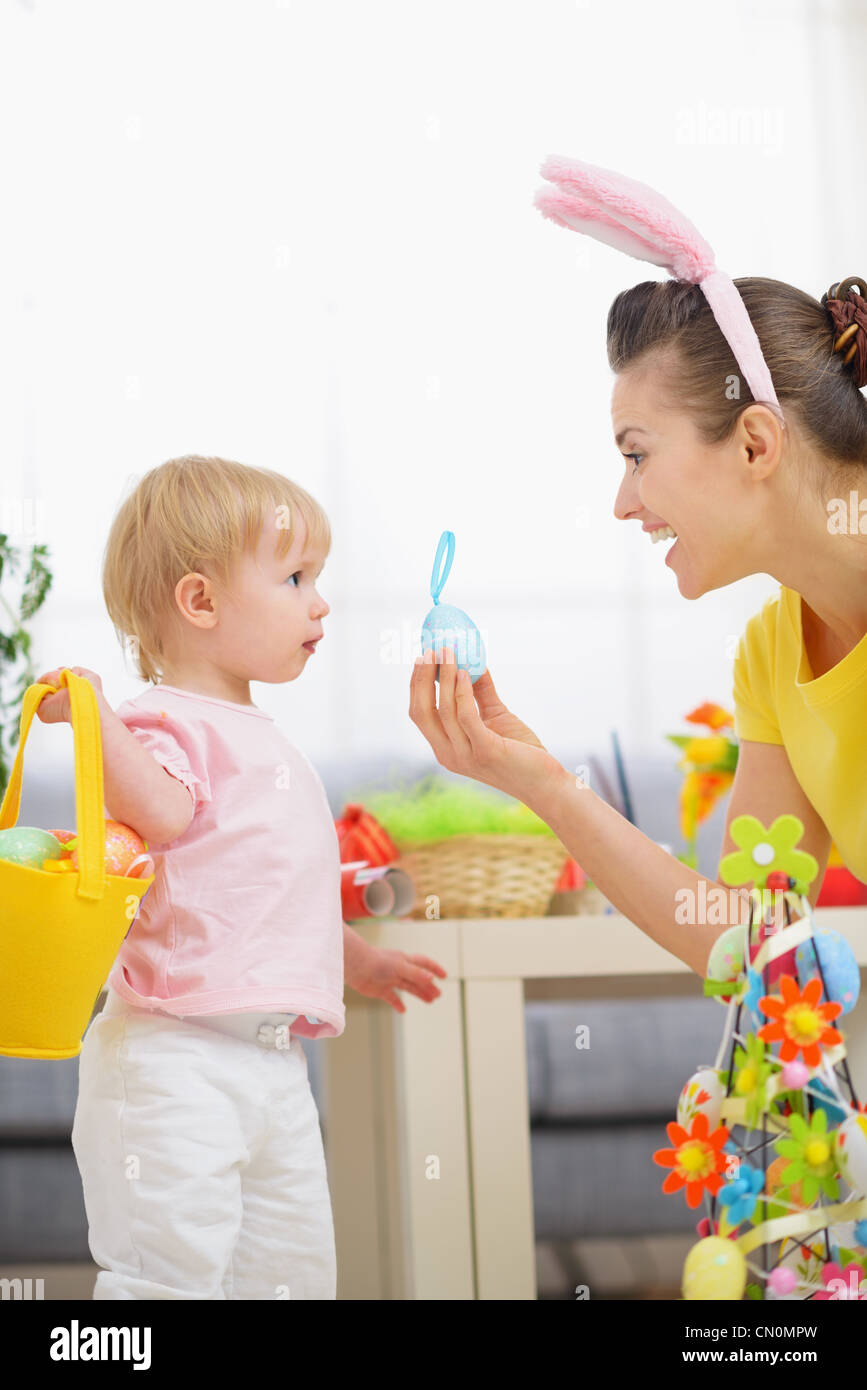 Mother helping baby collecting Easter eggs Stock Photo - Alamy
