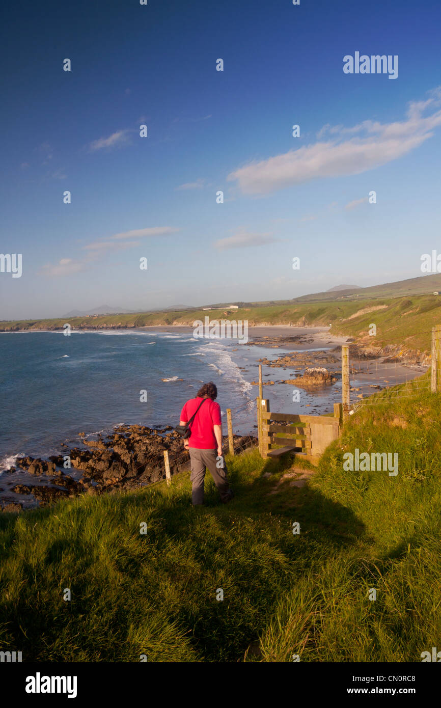 Male walker on Wales Coast Path about to cross stile Traeth Penllech ...