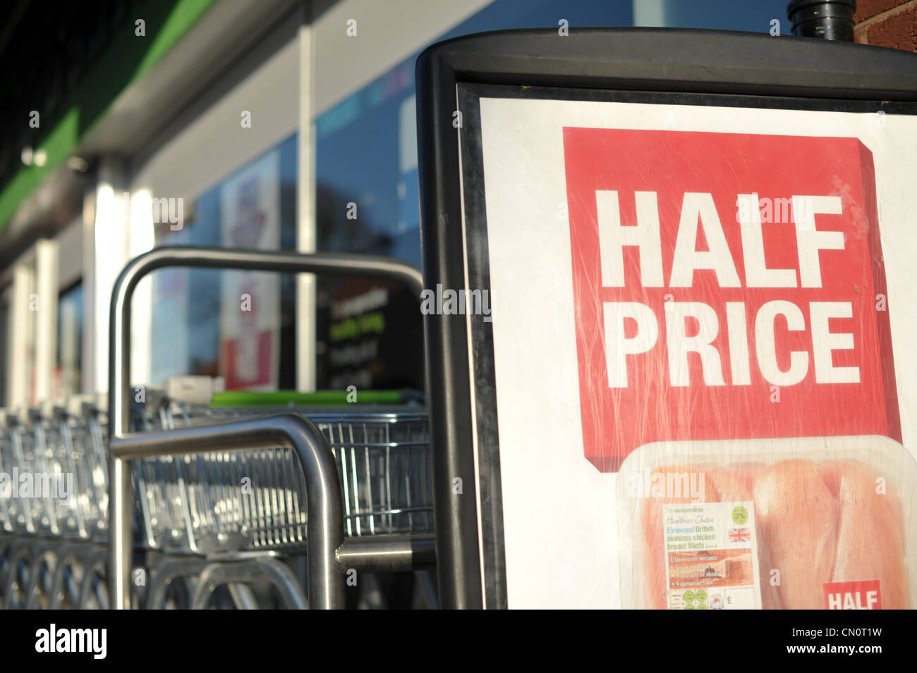 Half price sales poster in front of trolleys outside a supermarket ...