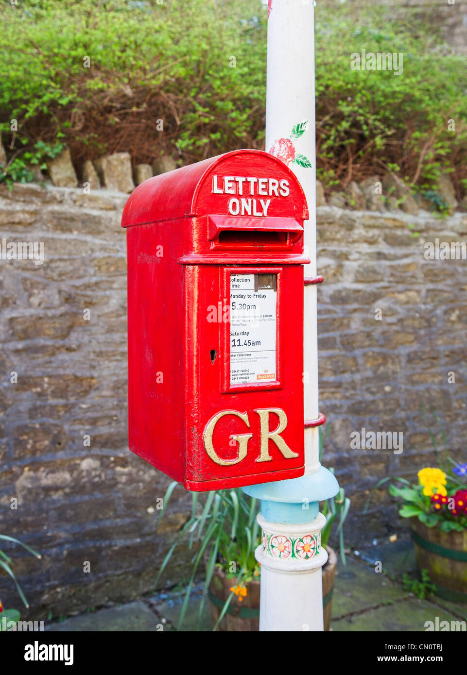Bright red post box attached to a white decorated and painted lamppost ...